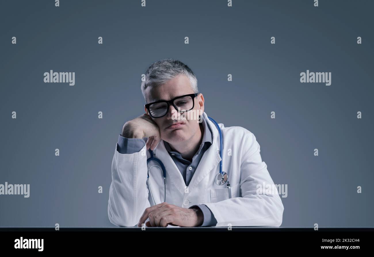 Disappointed sad doctor leaning on his arm, he feels hopeless and ...