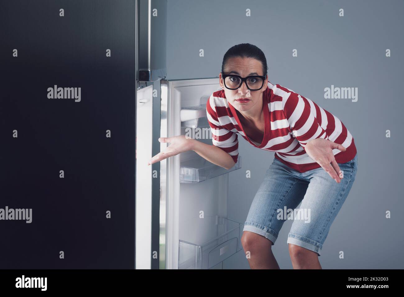 Empty fridge and disappointed woman shrugging Stock Photo - Alamy