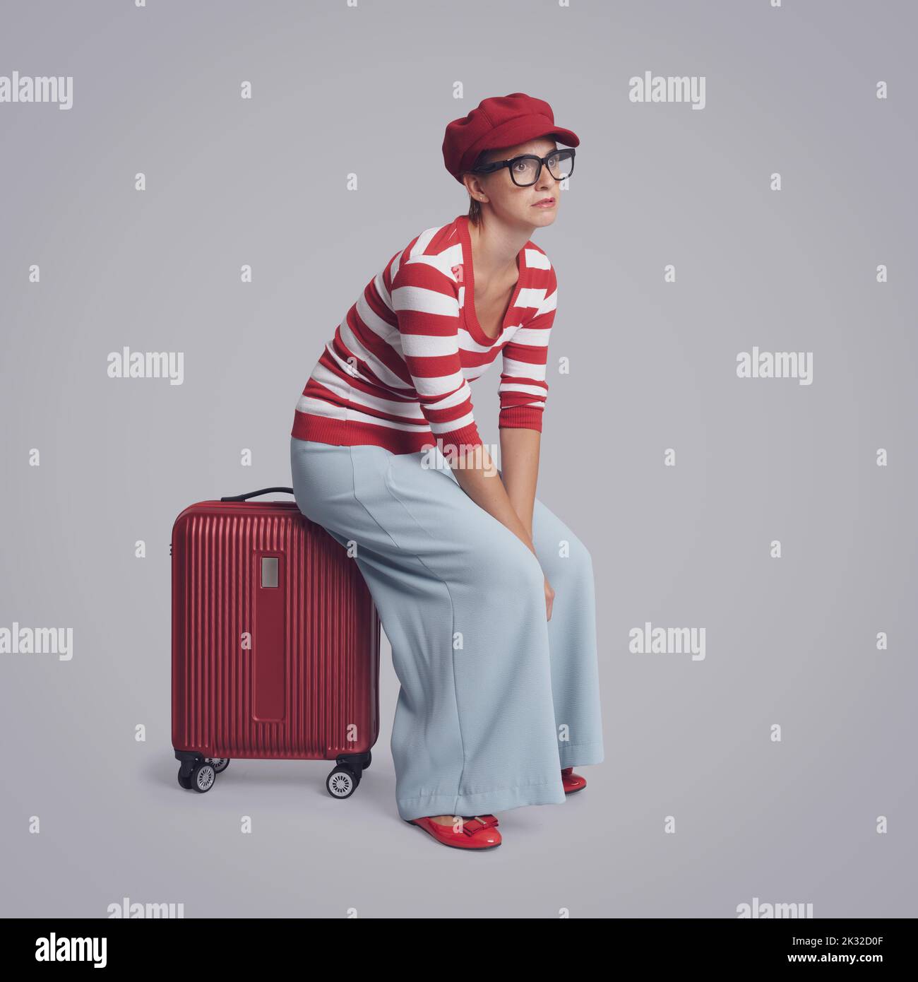 Sad disappointed traveler woman sitting on her suitcase and waiting ...