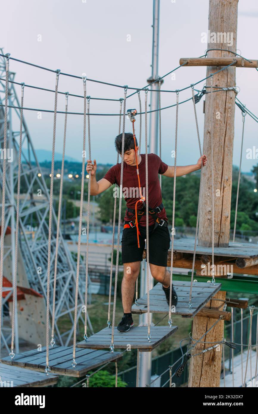 Adventure man walking on the wooden pillars at the adventure park Stock ...