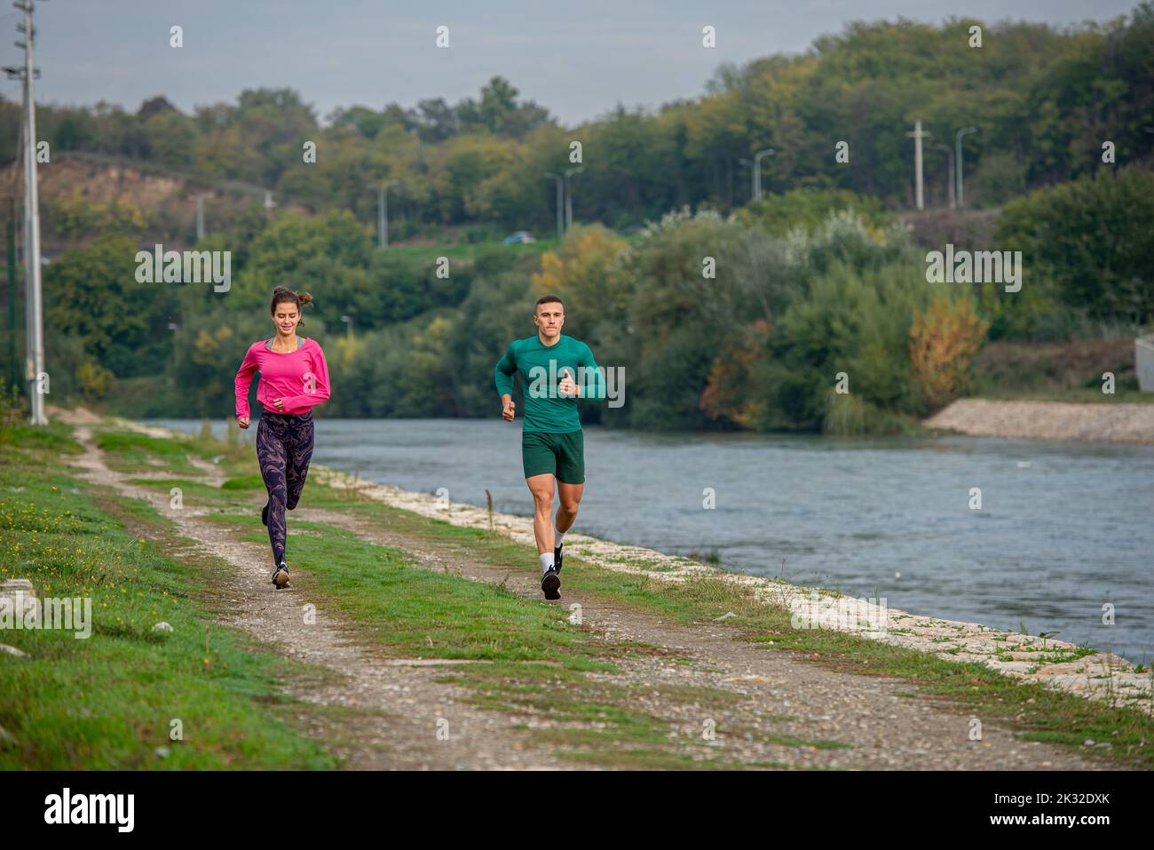 Two fit and attractive friends are doing some morning run by the river ...