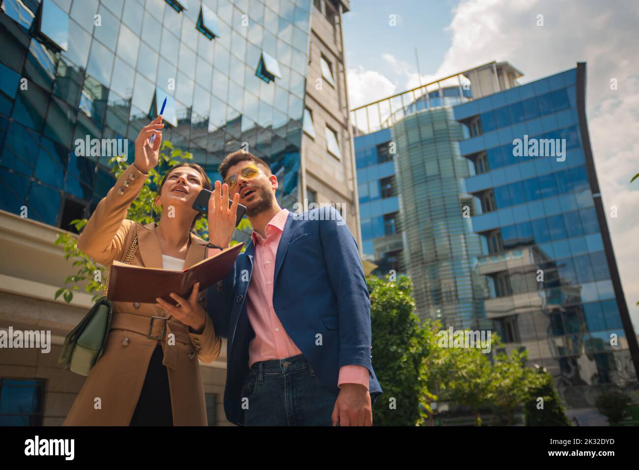 Young male and female business people are pointing somewhere and ...