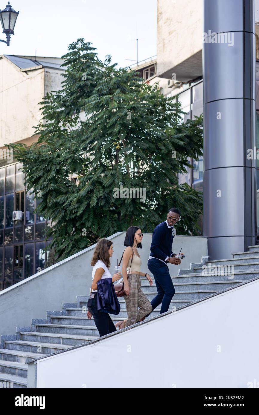 Three multiracial co workers are walking up the stairs together Stock ...