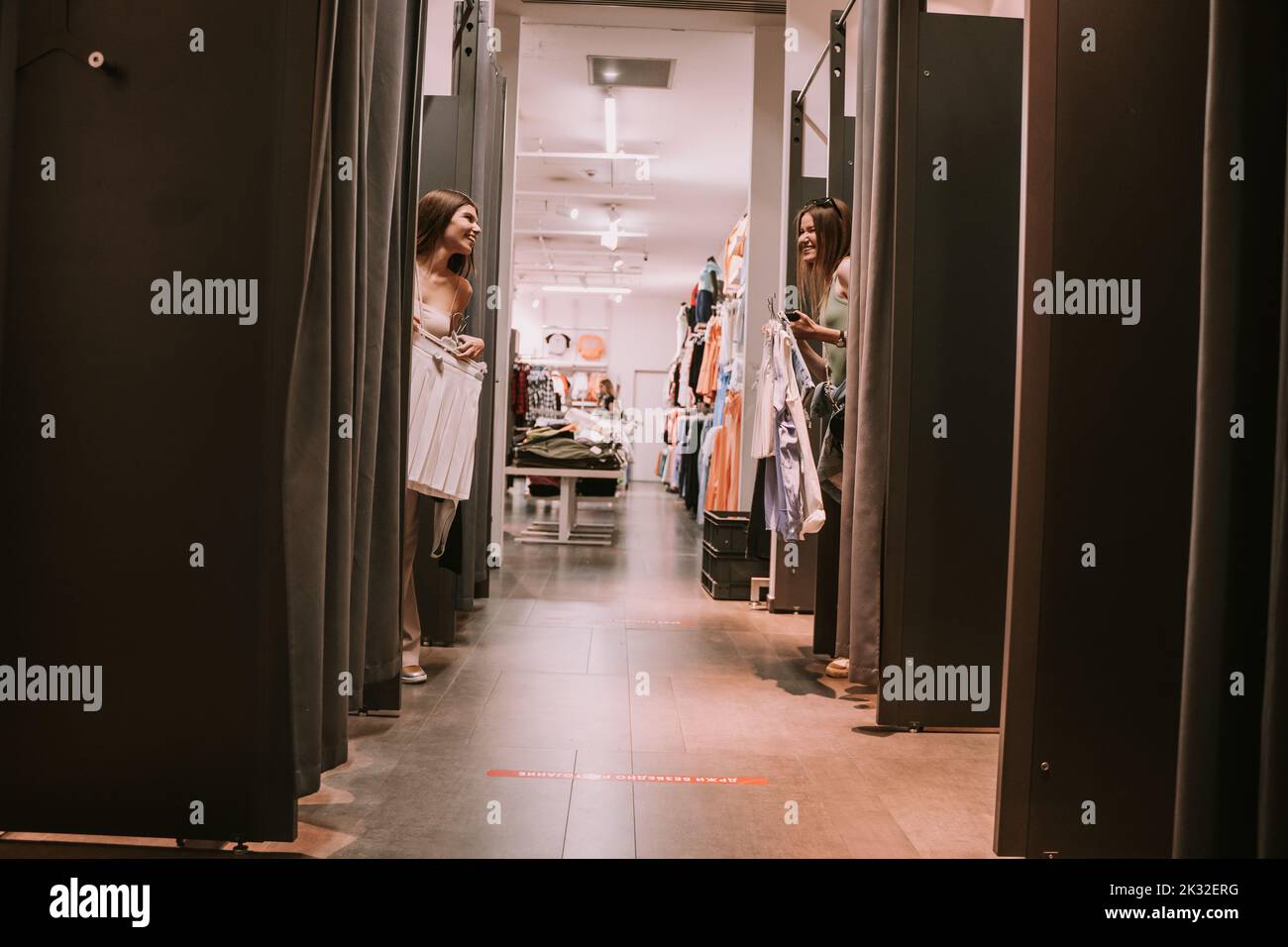 Two beautiful girls in the changeing room showing their clothes to ...