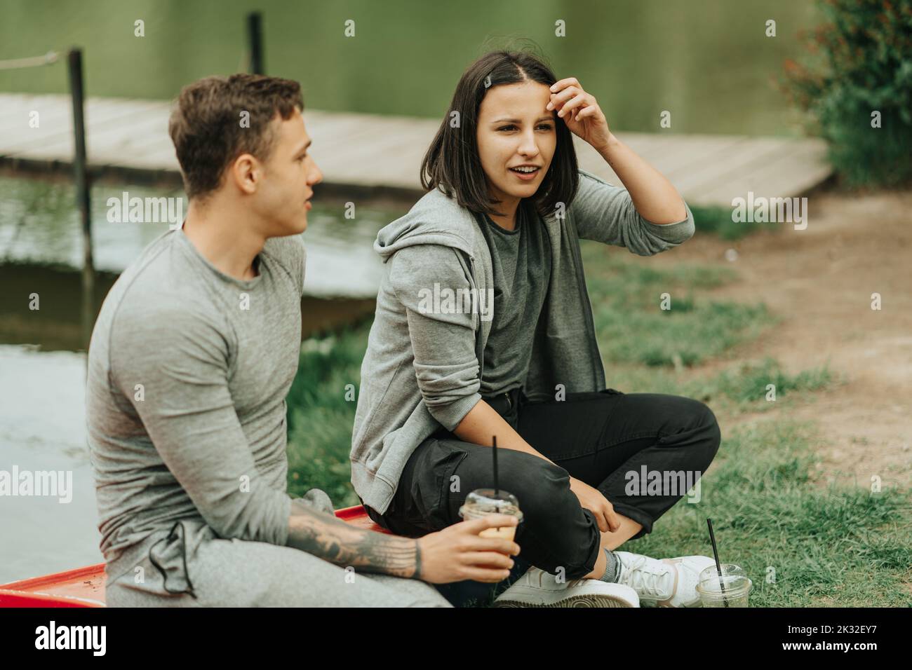 Beautiful couple sitting on a kayak in the park drinking orange juice ...