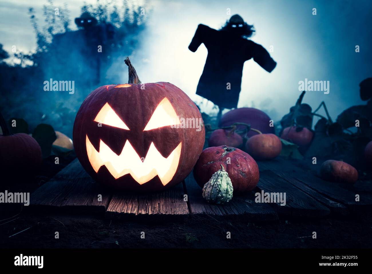 Spooky Halloween pumpkin on field with scarecrows and smoke. Background ...