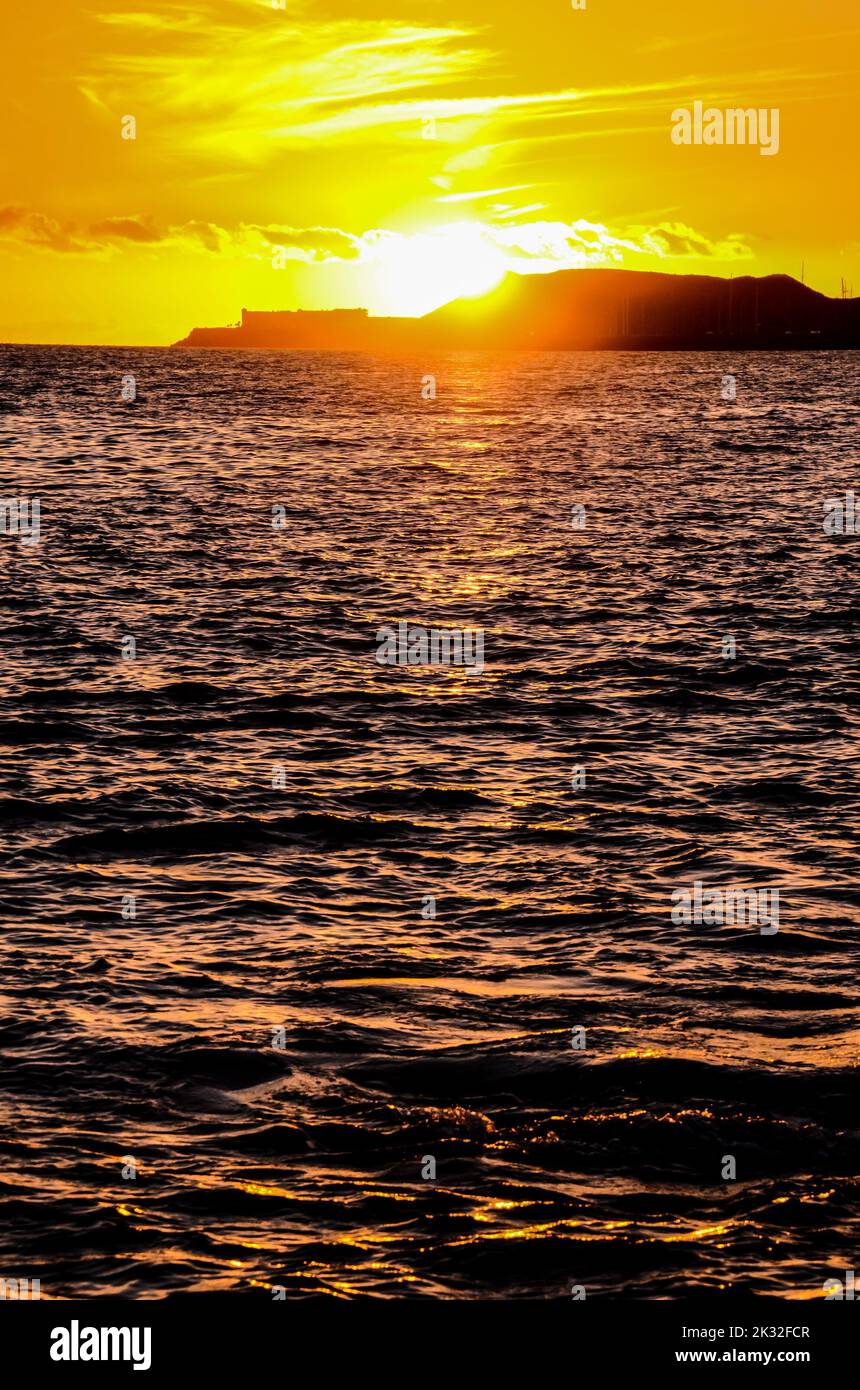 The vertical view of water waves before the hill under the sunset sky ...