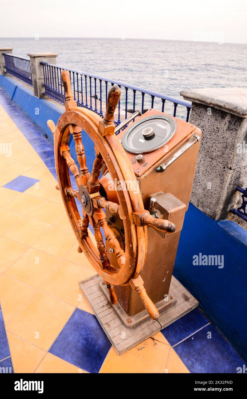 A vertical view of the old wooden vintage helm wheel by the fence ...