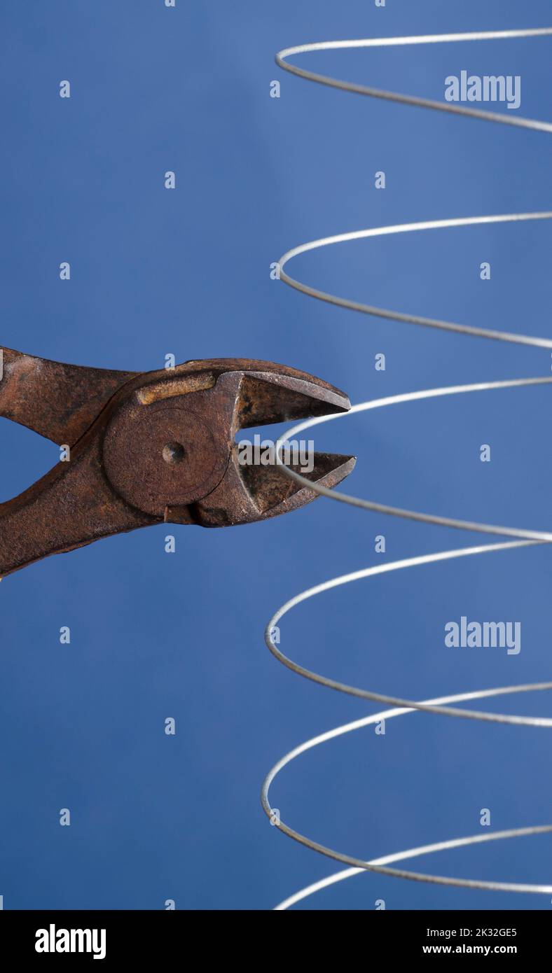 coiled metal wire cutting pliers, blue background Stock Photo - Alamy