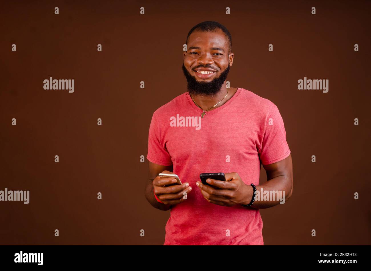 excited african man using two cellphone to send message Stock Photo - Alamy