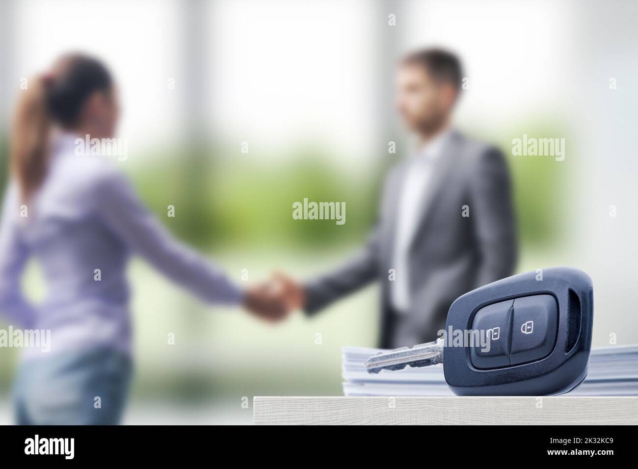 Customer and car salesman shaking hands at the car dealership, car keys ...