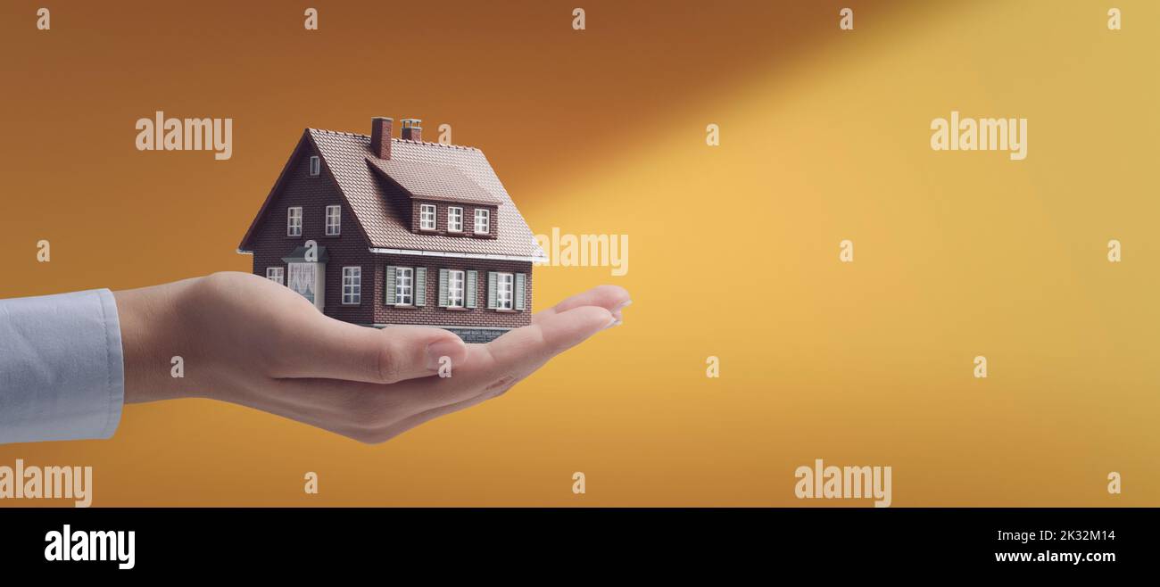 Hand holding a model house: home insurance and real estate concept ...
