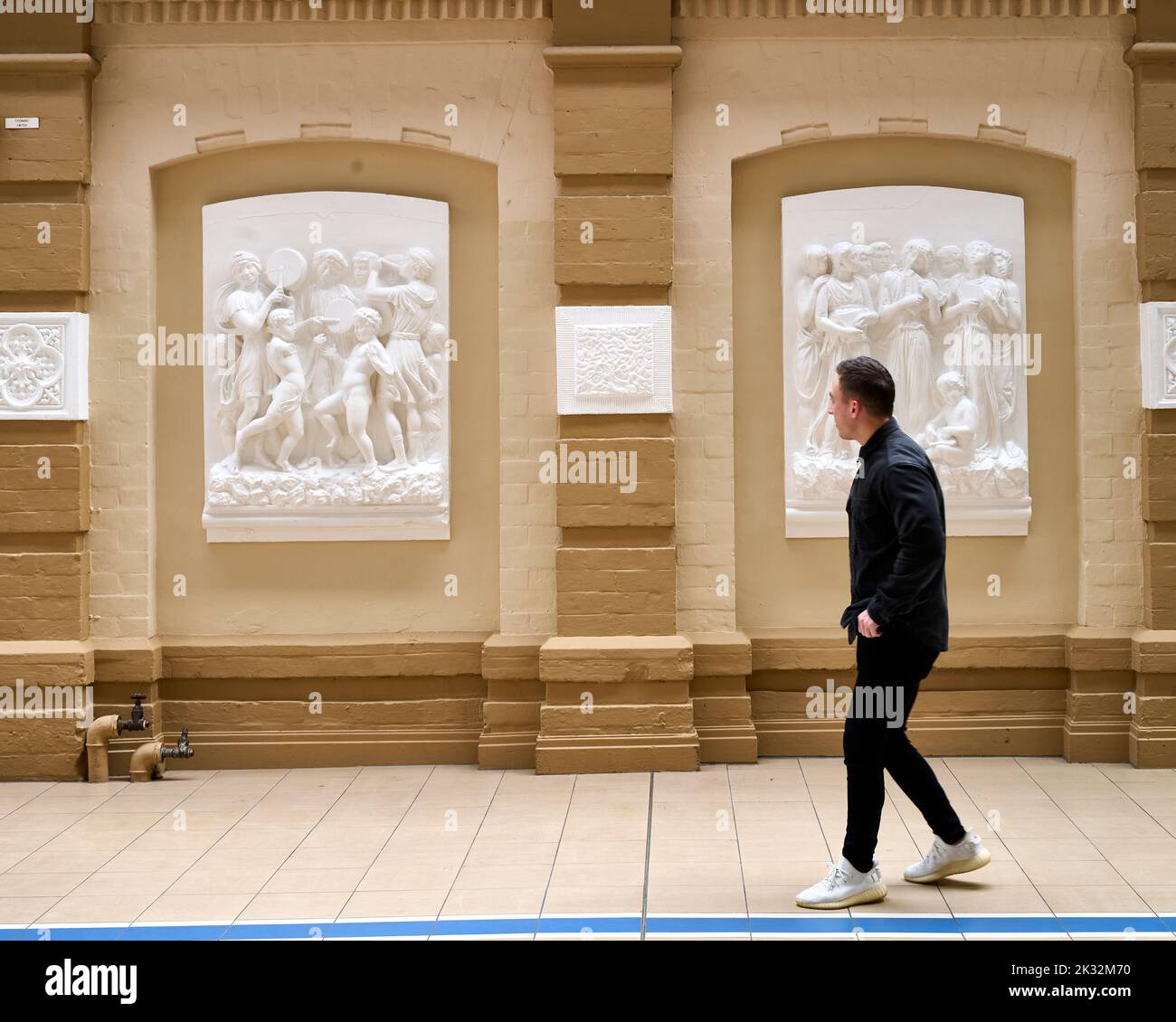 Man walking past entertainment theamed bas-reliefs on the walls of the ...