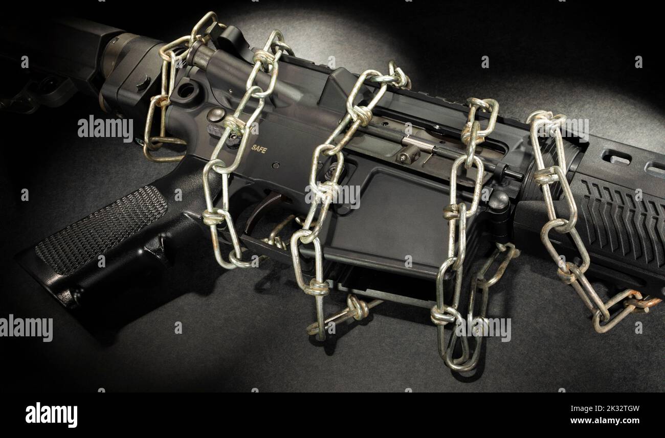 Chain around an assault rifle on a black background Stock Photo - Alamy