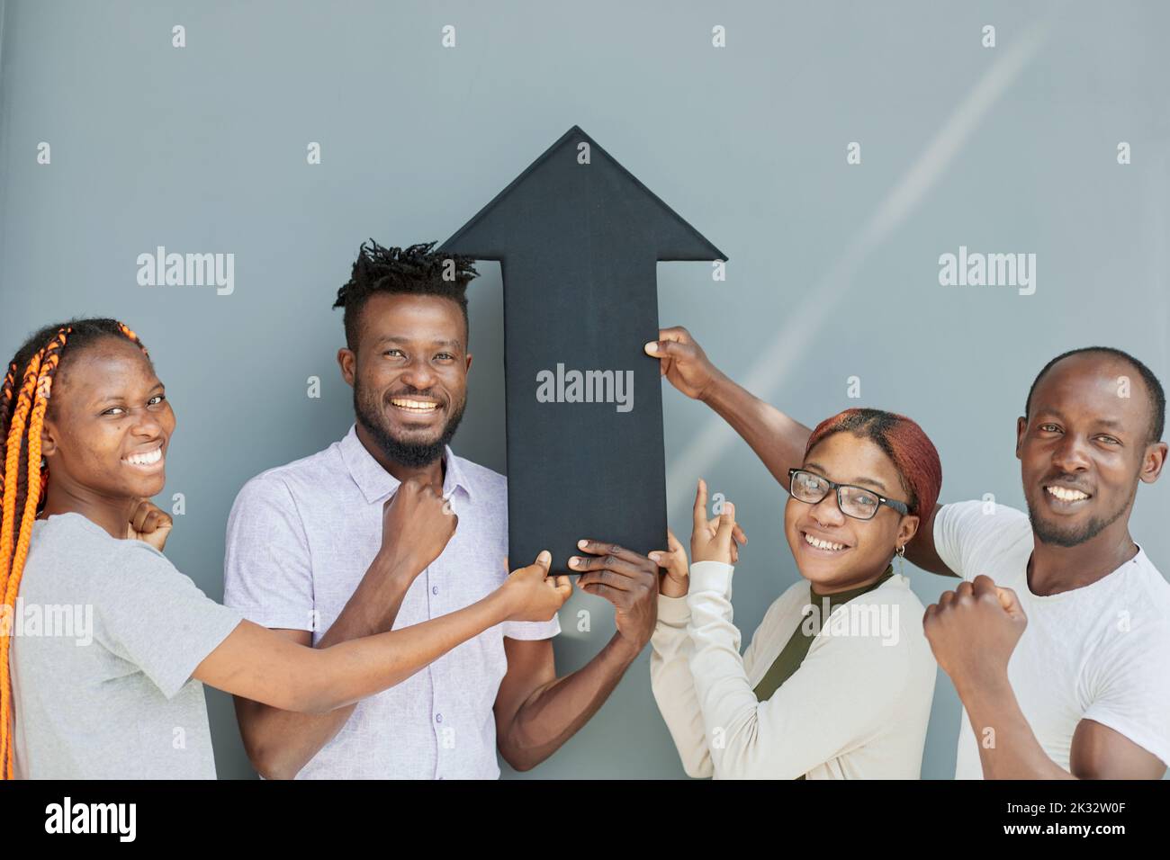 Young african american friends holding black arrow Stock Photo - Alamy