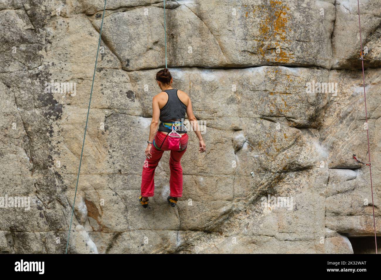 A young woman with a rope engaged in the sports of rock climbing on the ...