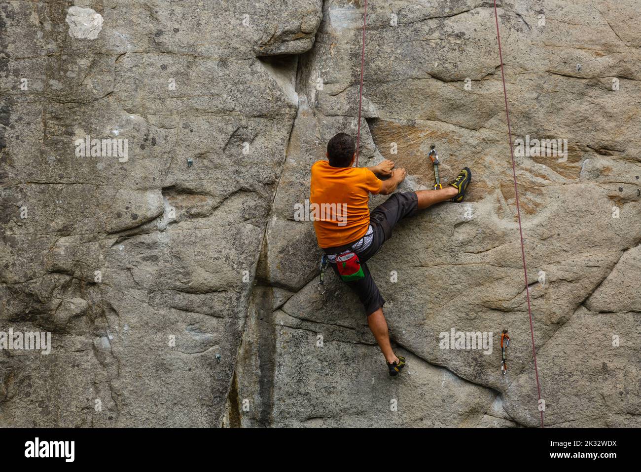 A young woman with a rope engaged in the sports of rock climbing on the ...