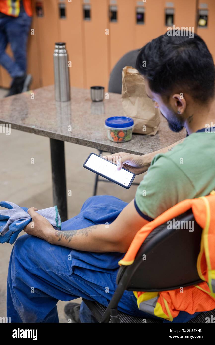 Worker using phone at lunch break in locker room Stock Photo - Alamy