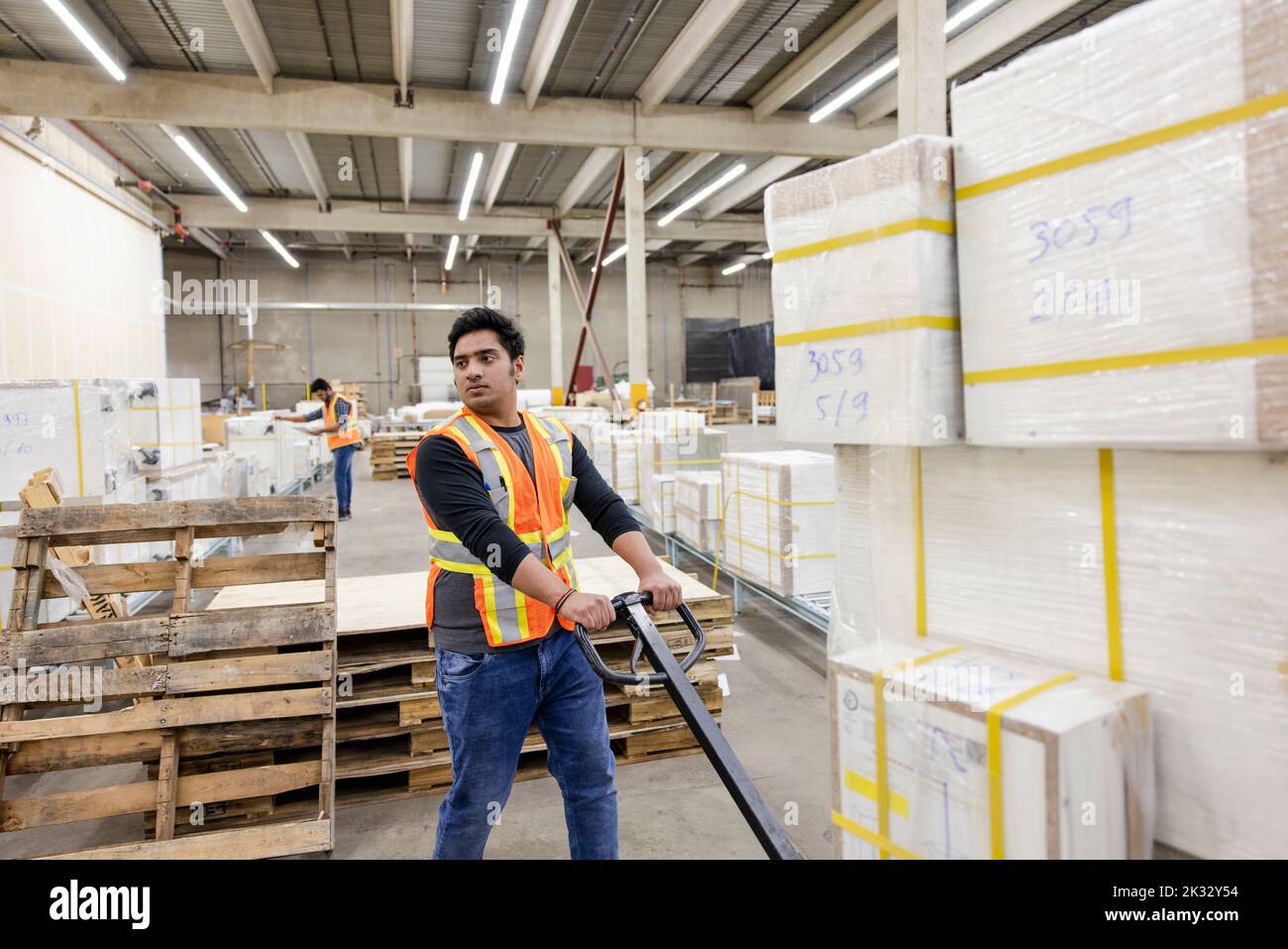 Worker moving cargo in distribution warehouse Stock Photo - Alamy