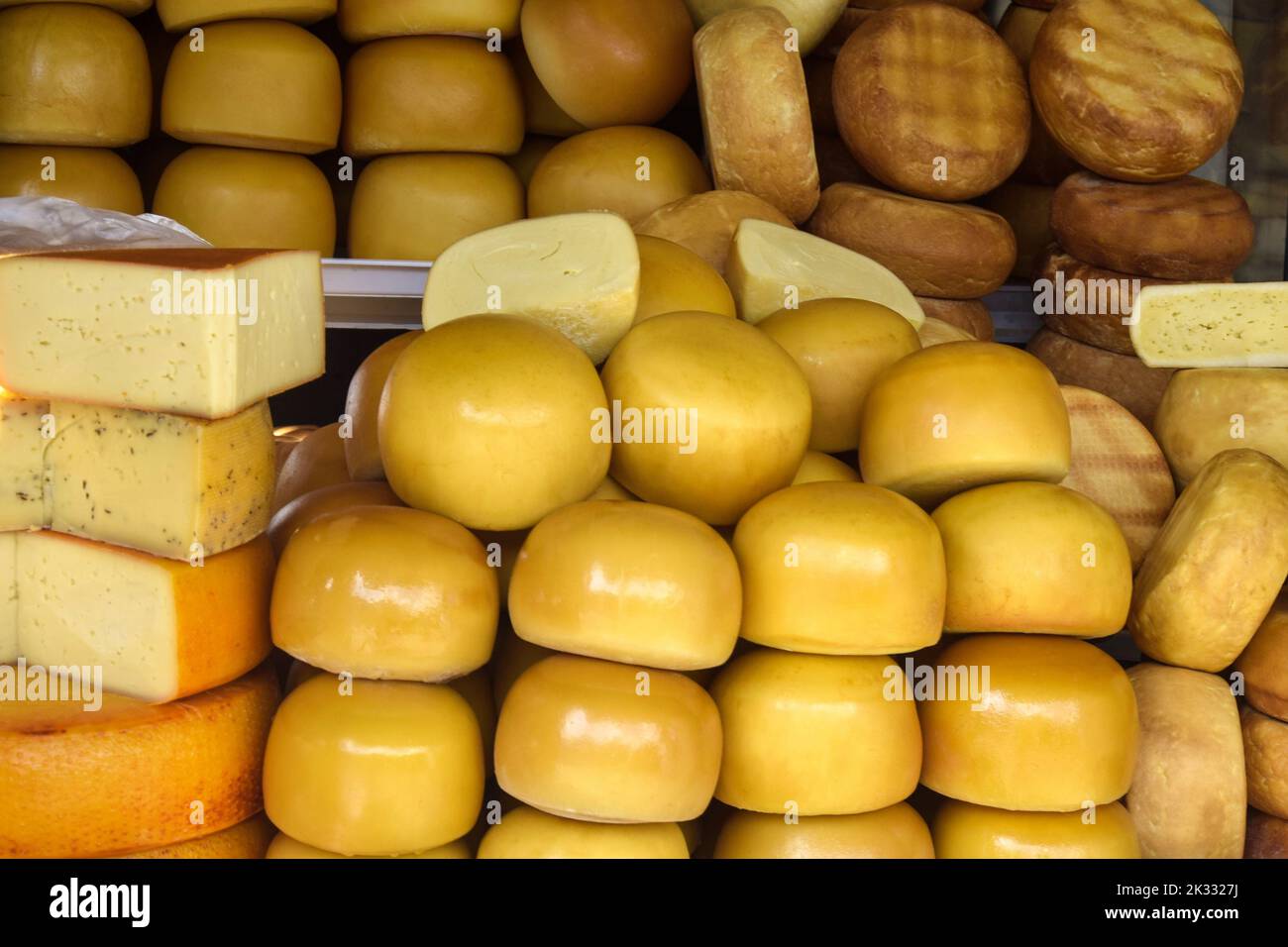 Cheese heads of different colors and sizes are stacked on counter. Fair ...