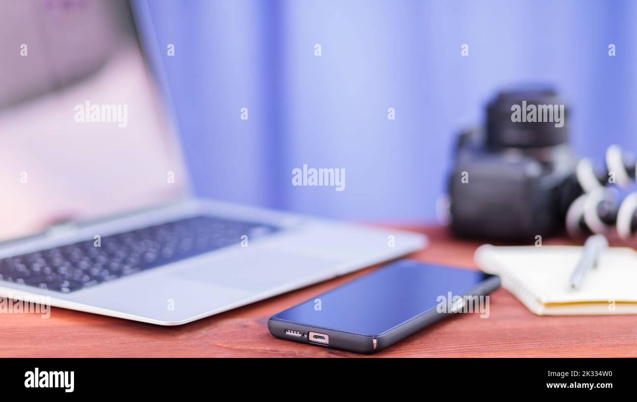 Vlogger workplace. Laptop, smartphone, notebook and camera on a wooden ...