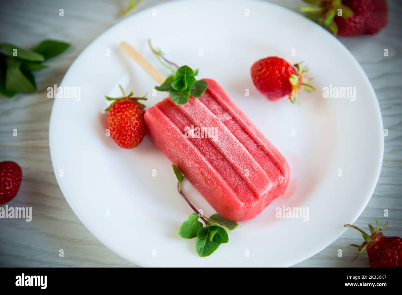 cooked homemade strawberry ice cream on a stick in a plate with ...