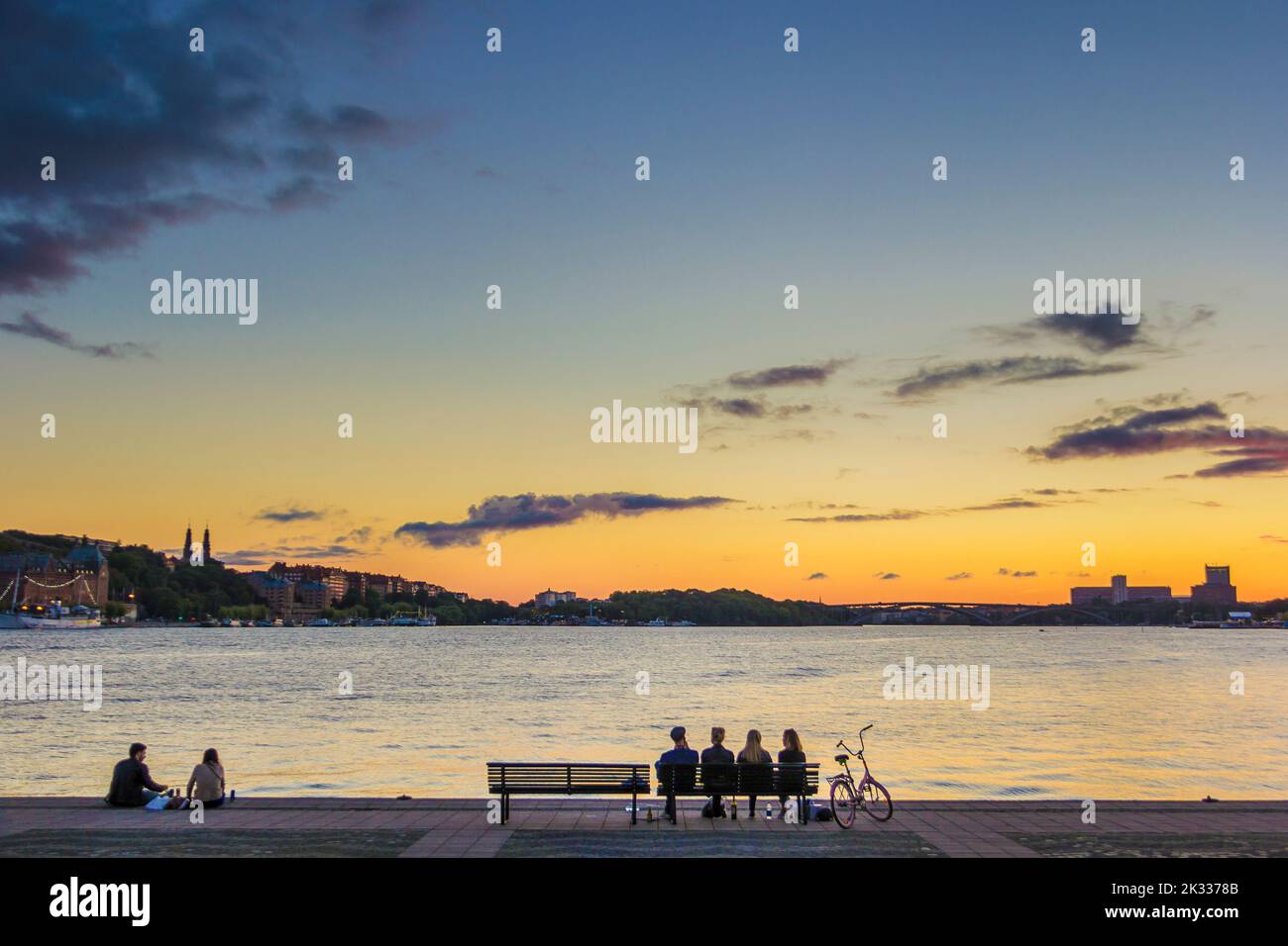 Groups of people sitting on wooden benches enjoy the sunset view Stock ...