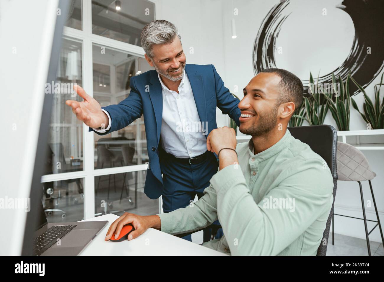 Two multiethnic business colleagues working together in modern office ...