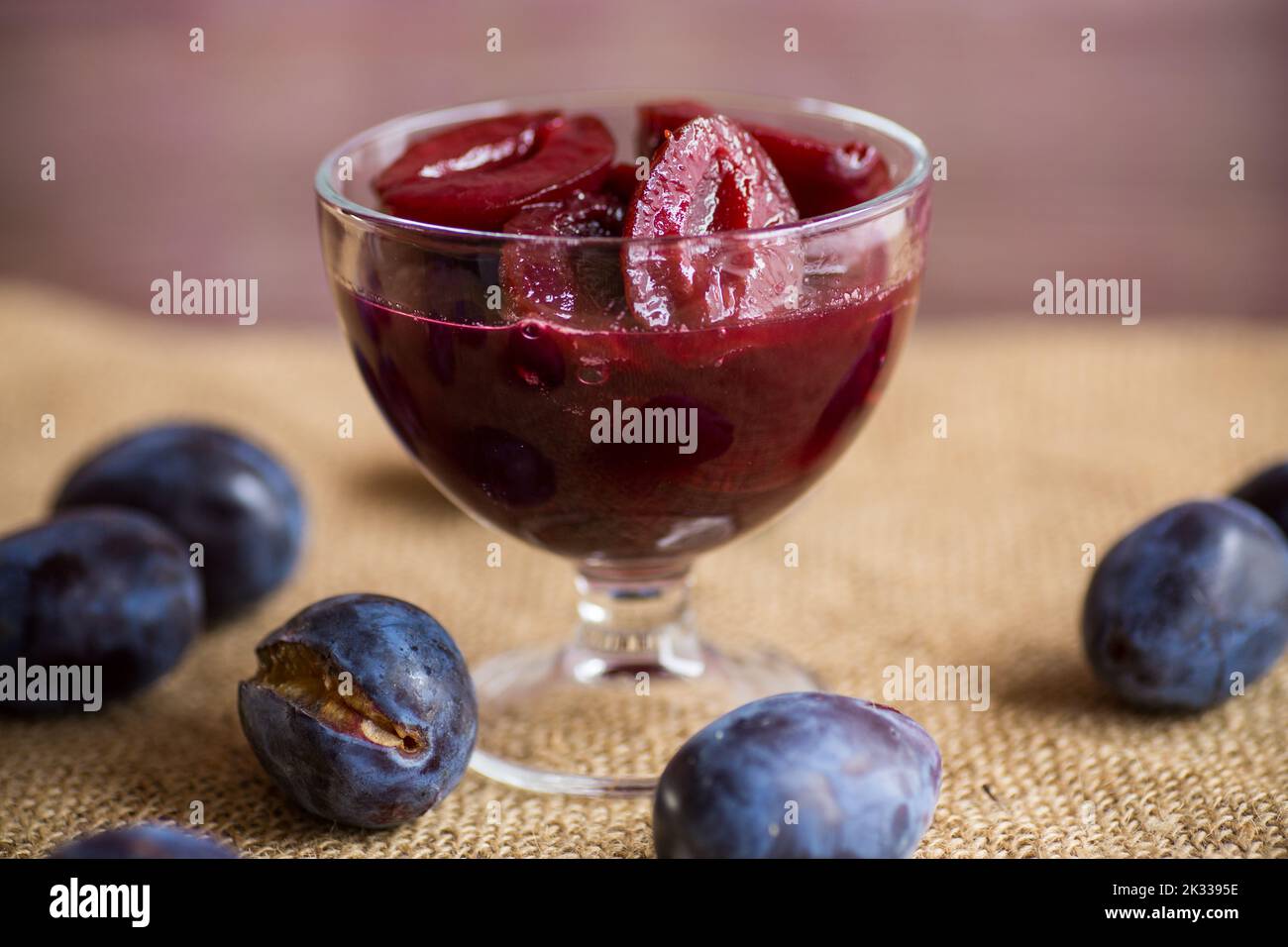 Sweet plums in syrup, in a glass bowl on a wooden table Stock Photo - Alamy