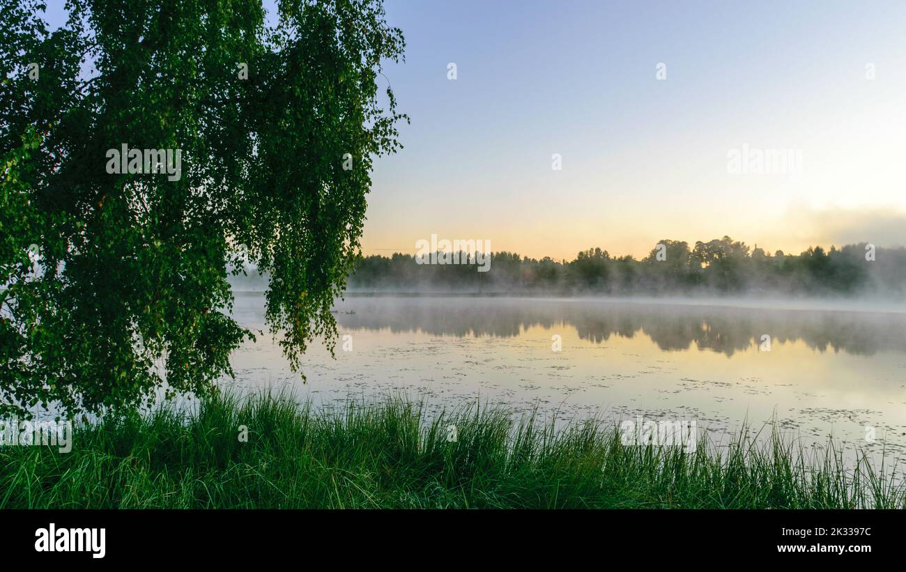 early autumn morning by the lake, fog over the surface of the water, a ...