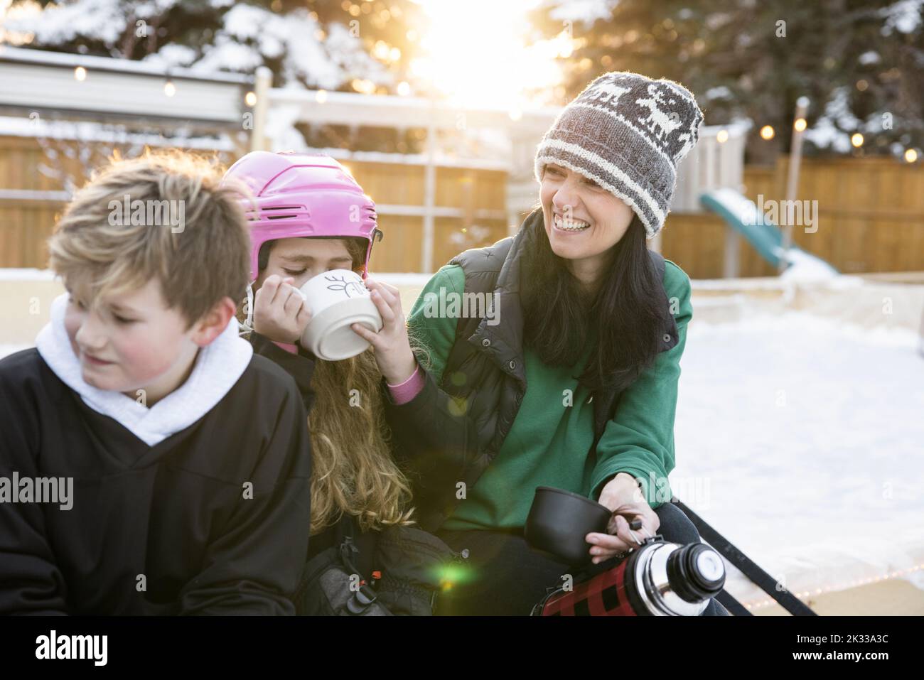 Happy family enjoying hot cocoa at backyard ice rink Stock Photo - Alamy