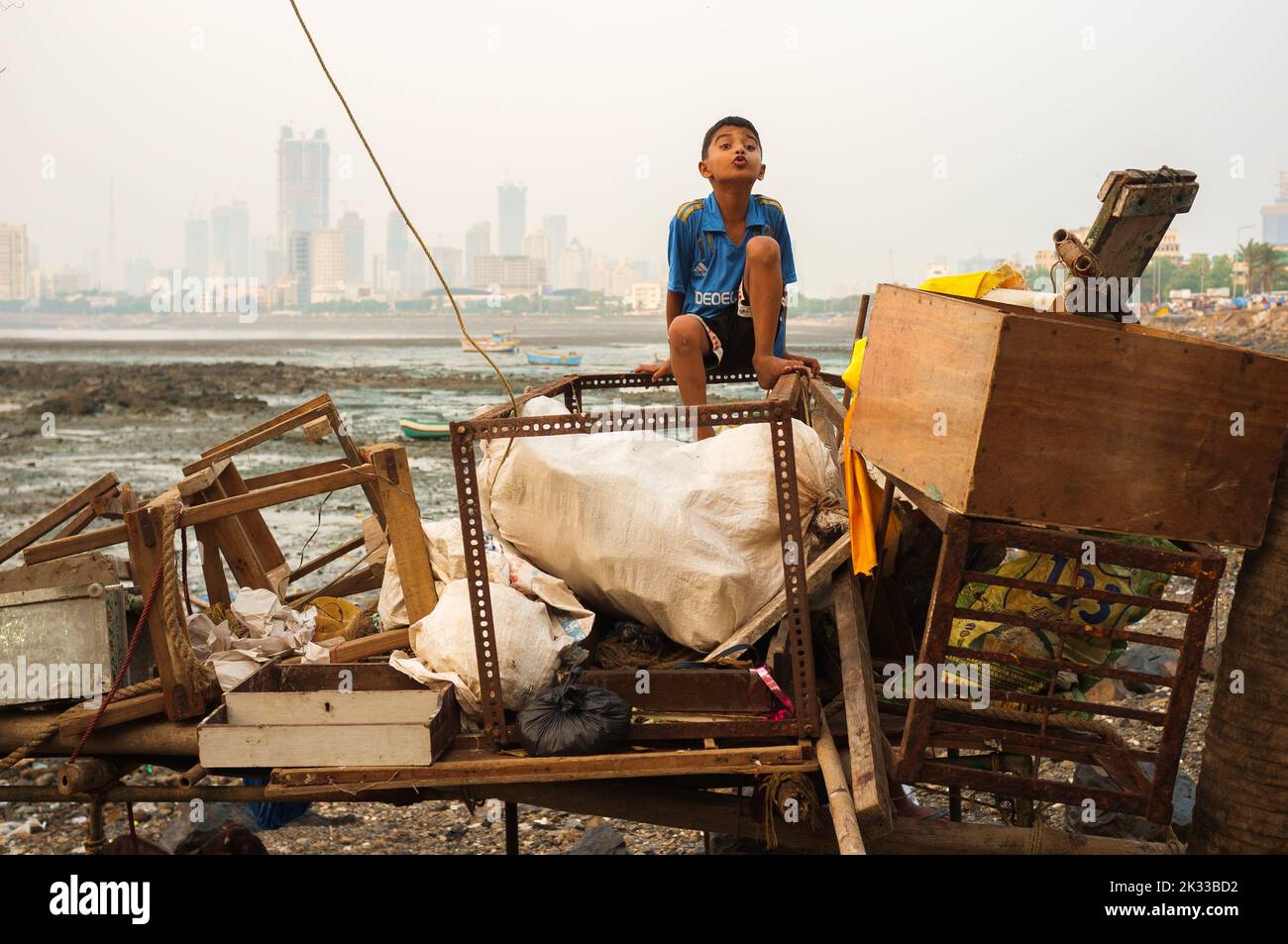 A young Indian boy making faces on the pile of trash in Mumbai, India ...