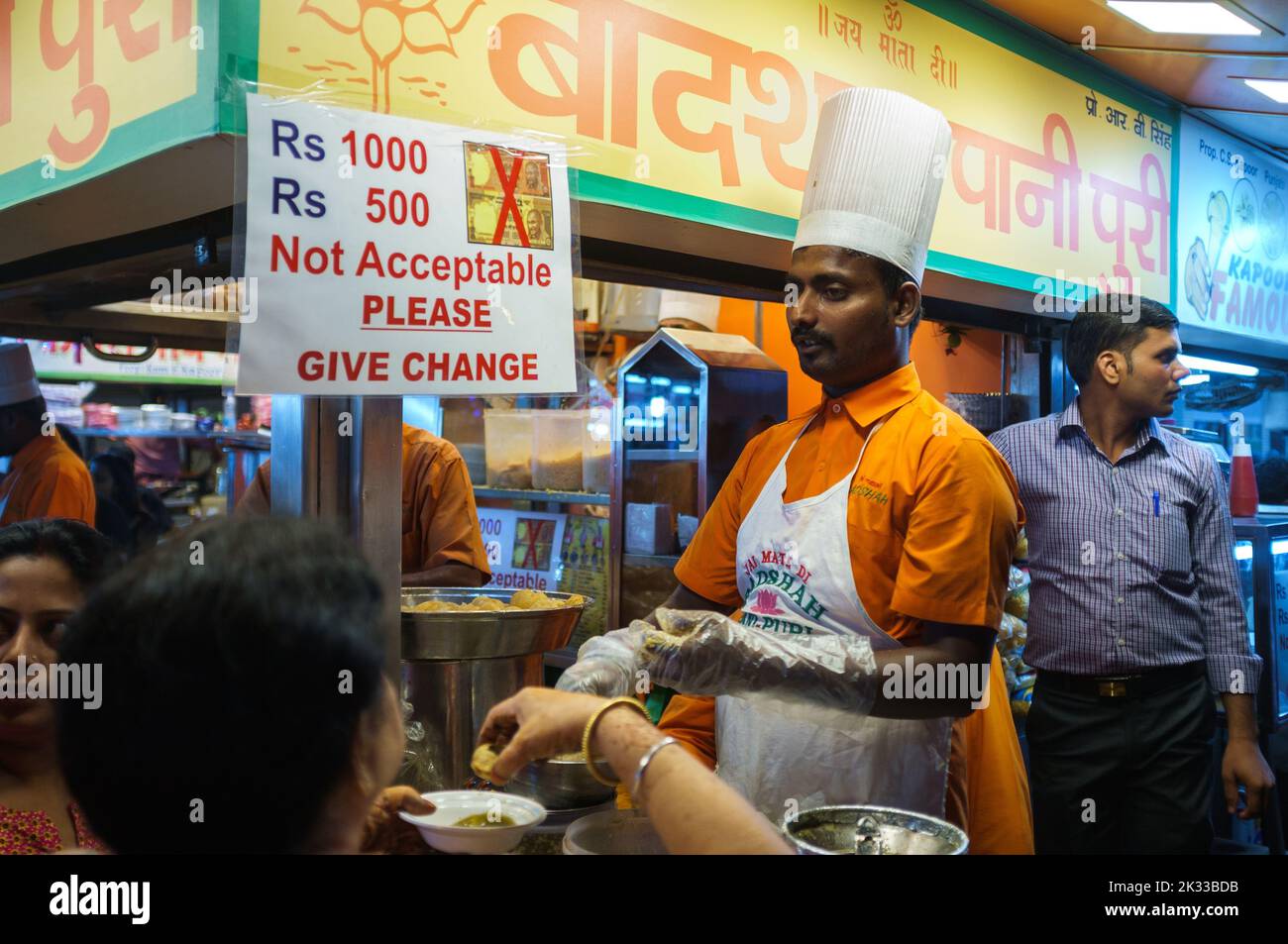 An Indian cook preparing street food at the stall in Mumbai at night ...