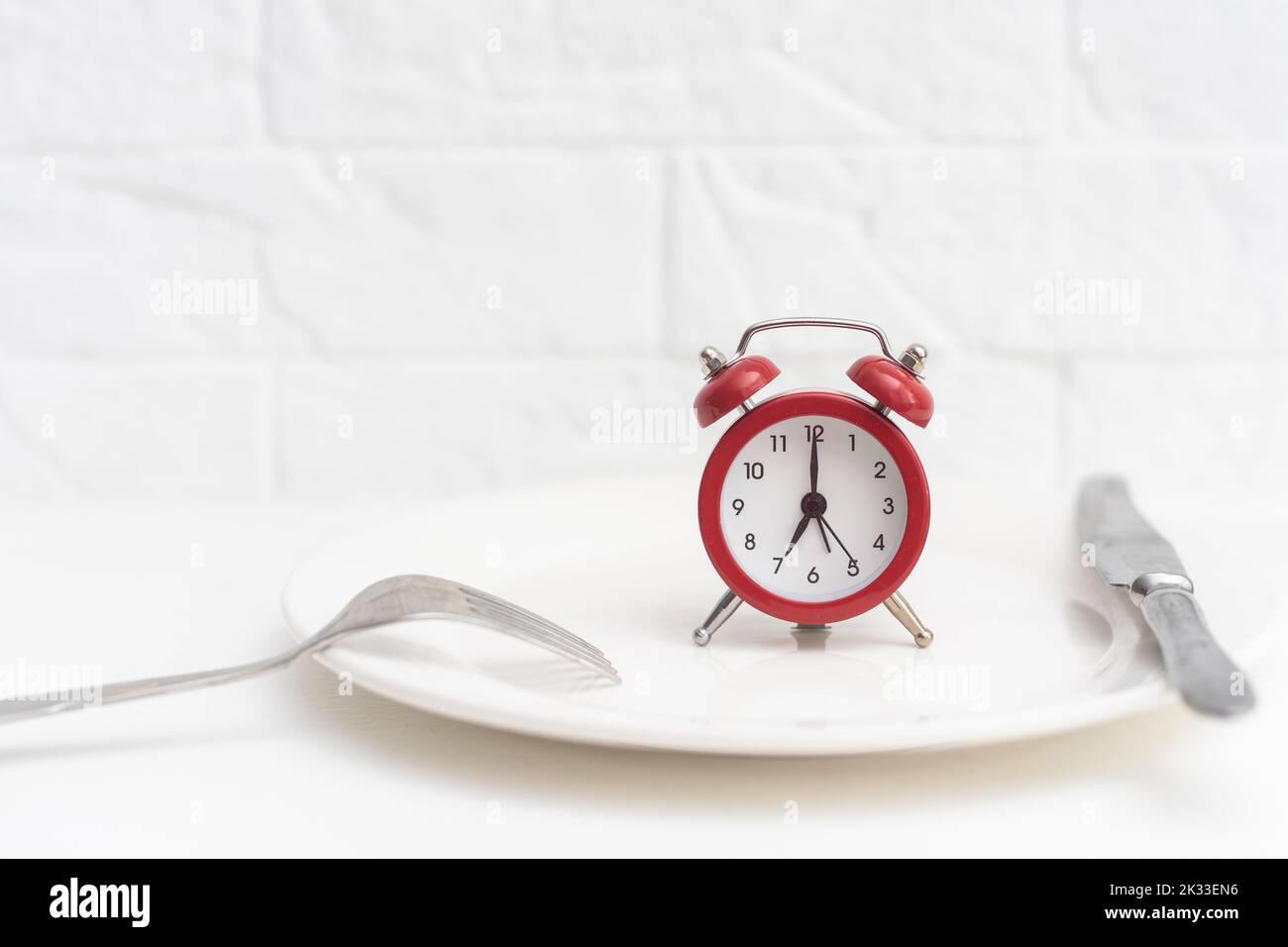 Intermittent fasting concept. Red alarm clock on an empty plate Stock ...