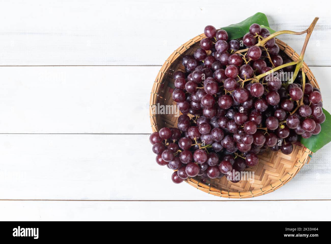 Champagne grapes in bamboo basket and on white wood background ...