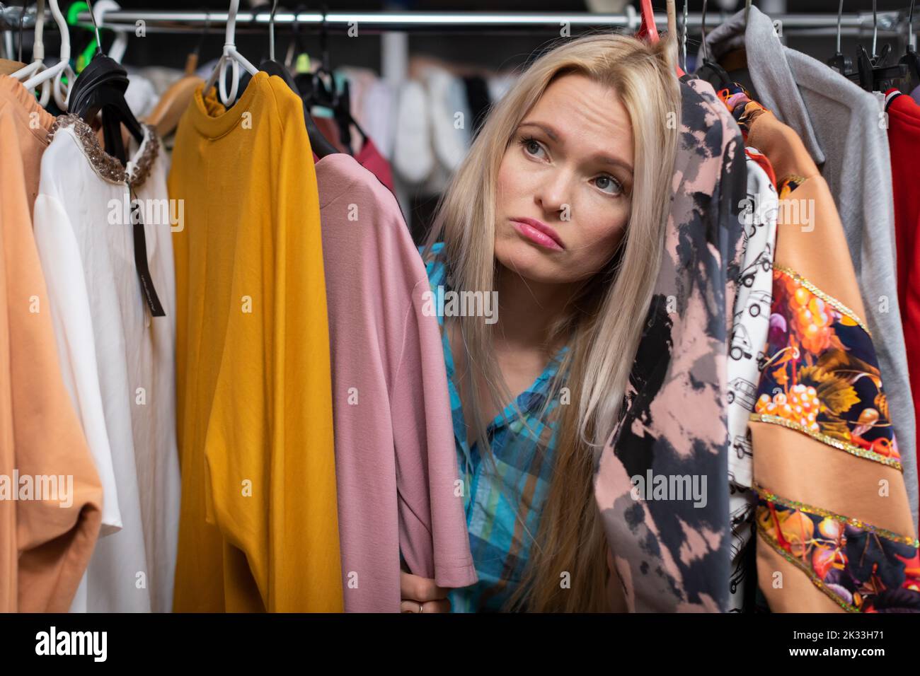 A sad blonde woman shopping in a clothing store Stock Photo - Alamy