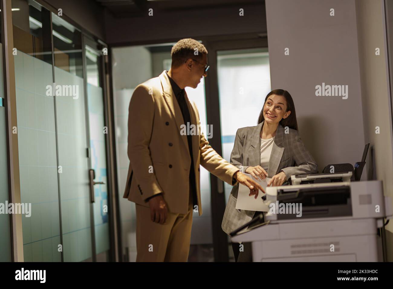 Two business people are talking while scanning documents on a scanner ...