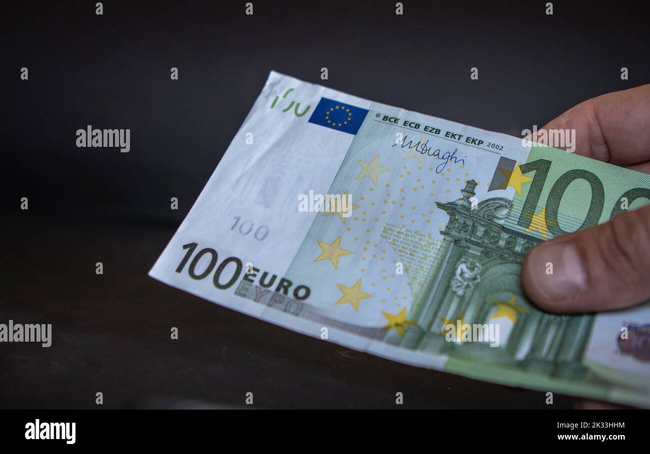 Right Hand Holds Stack of 100 Euro Banknotes on black background, The ... Right Hand Holds Stack of 100 Euro Banknotes on black background, The ...