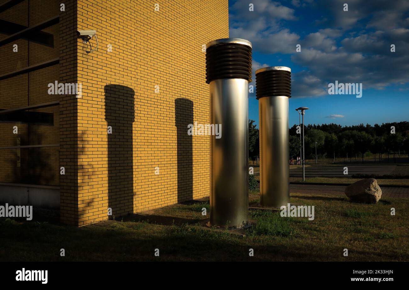 Two ventilation towers built next to a university building and their ...