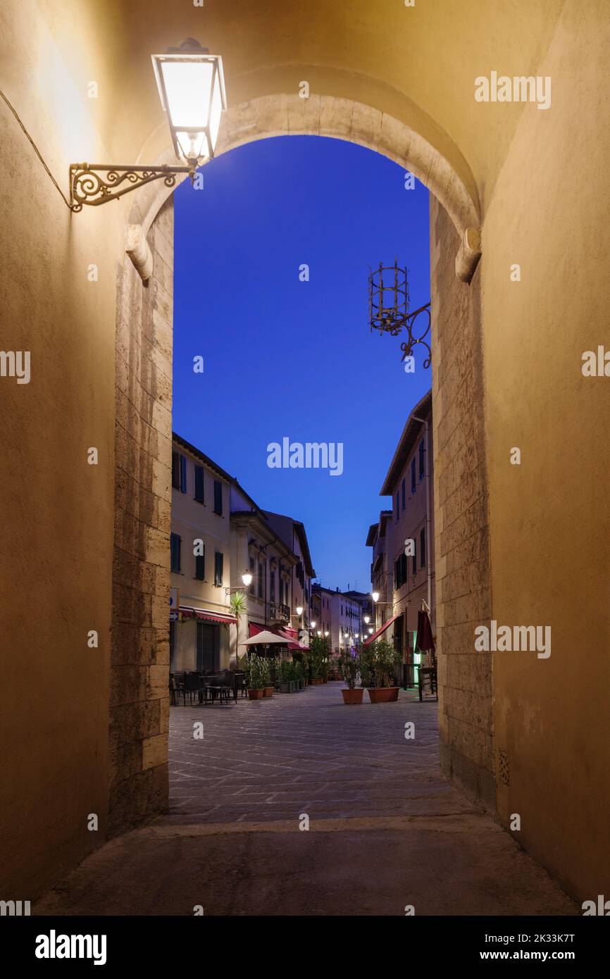 Night scene along typical Italian narrow street of Piombino old town ...