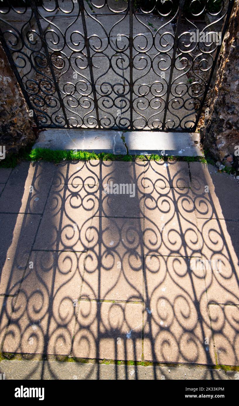 A black entrance cast iron gate with shadow on the ground Stock Photo ...