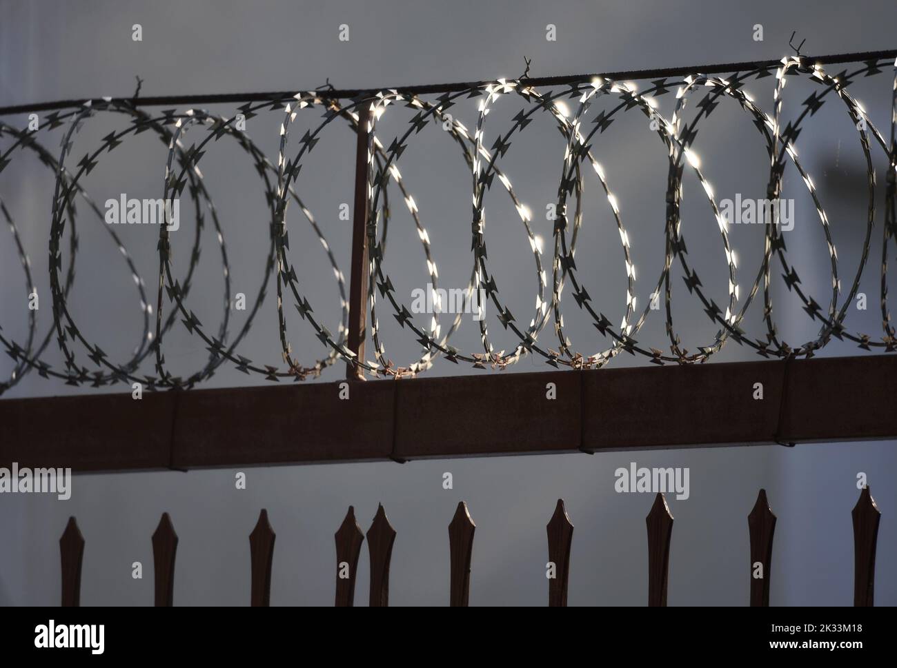 Metal fence with a sharp barbed wired top Stock Photo - Alamy