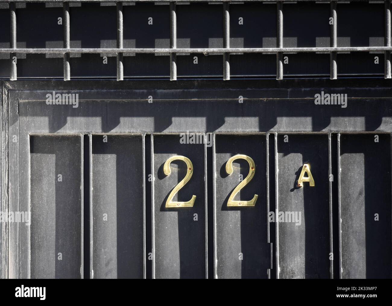 Antique brass street number on a handcrafted wrought iron entrance gate ...