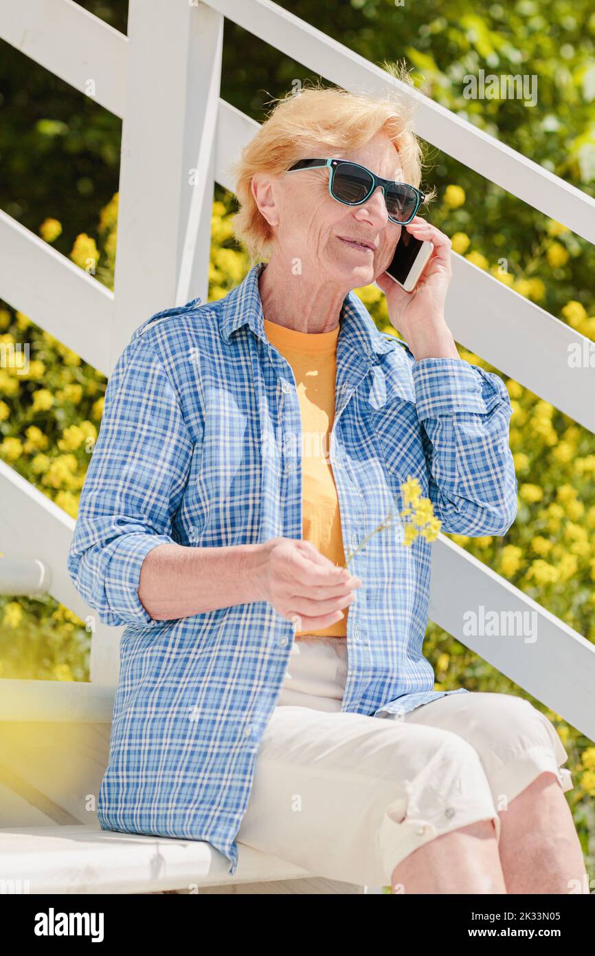 Mature woman sitting alone on the terrace of beach cafe and using ...