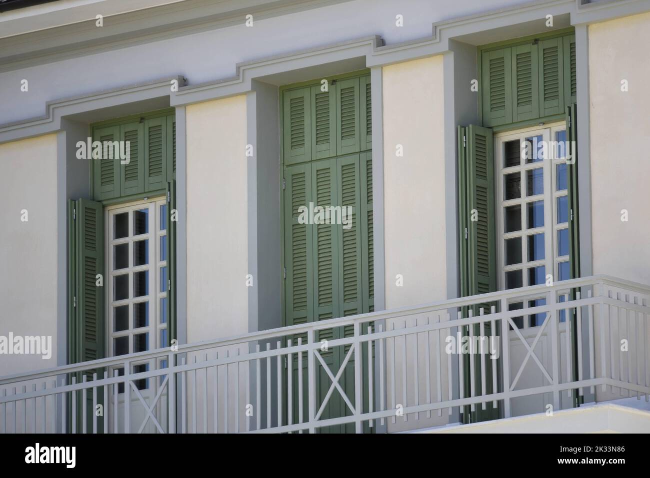 Neoclassical mansion facade with white windows, olive green wooden ...