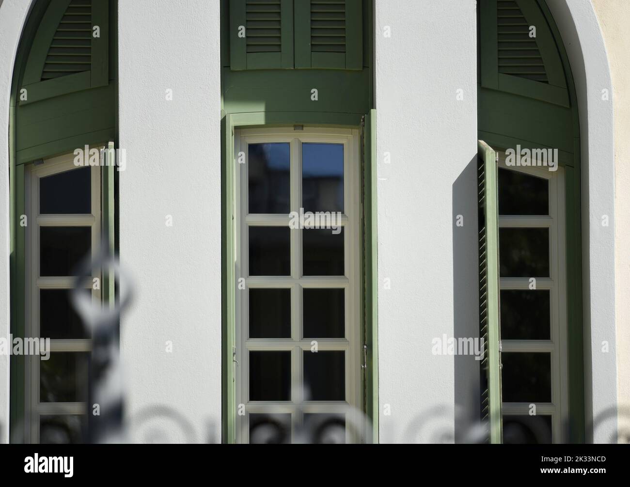 Luxury mansion symmetrical bay windows on an olive green stucco wall ...