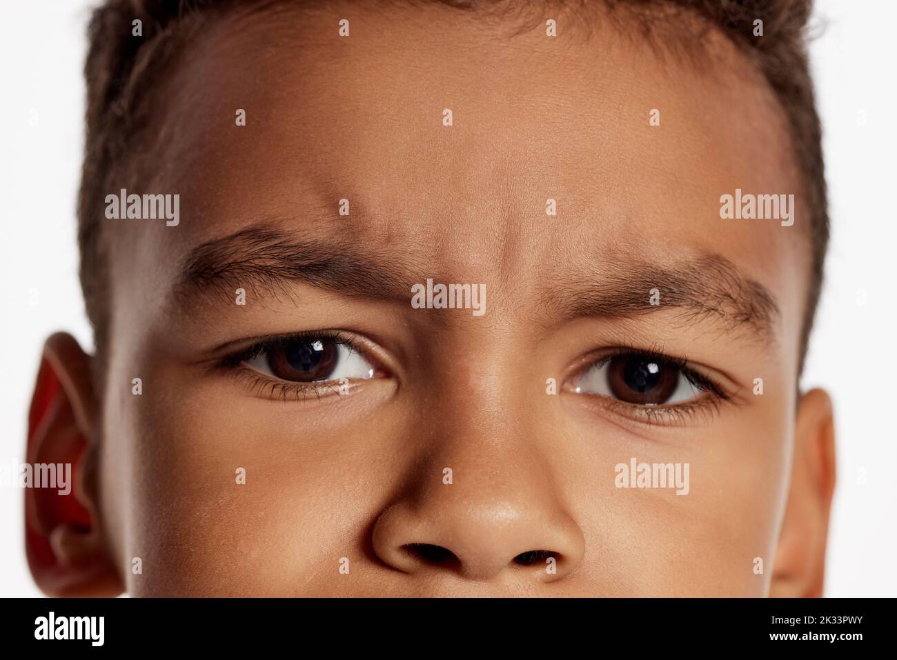 Close-up of little boy face with dark brown eyes expressing emotions ...