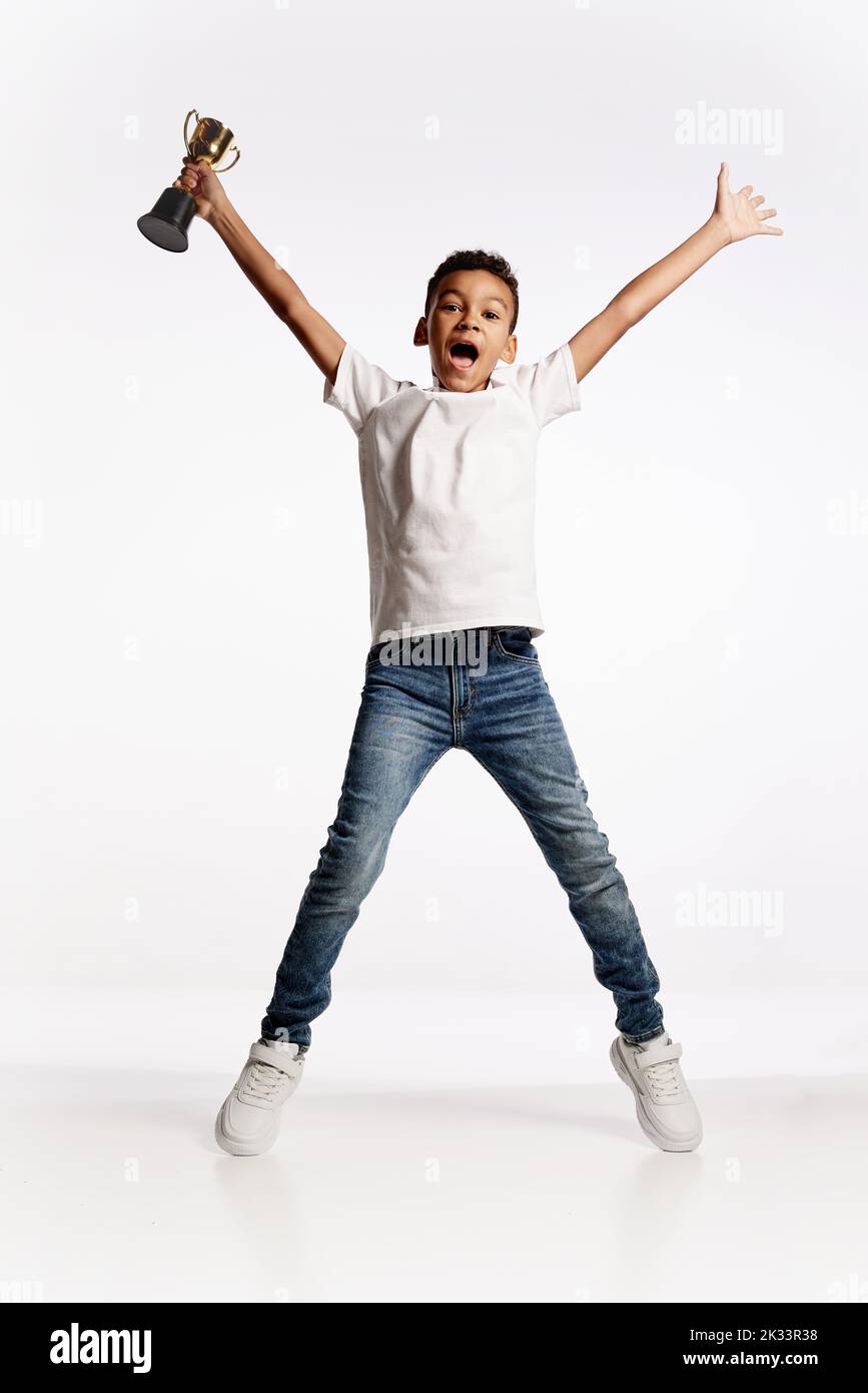 Winner emotions. Happy african little boy jumping with his prize ...