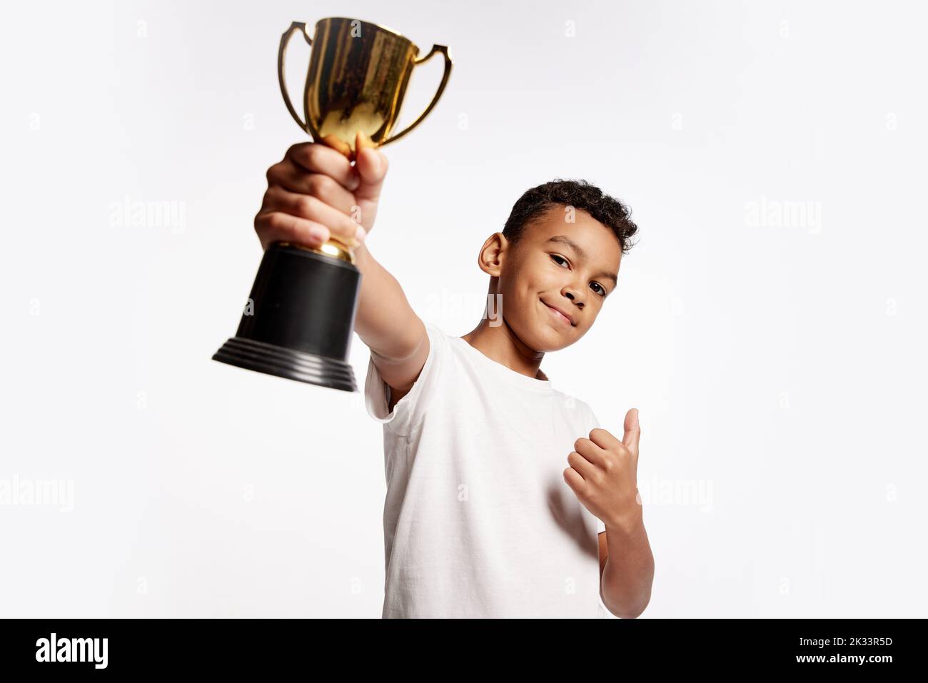 Happy african little boy in white tee showing his prize at camera ...