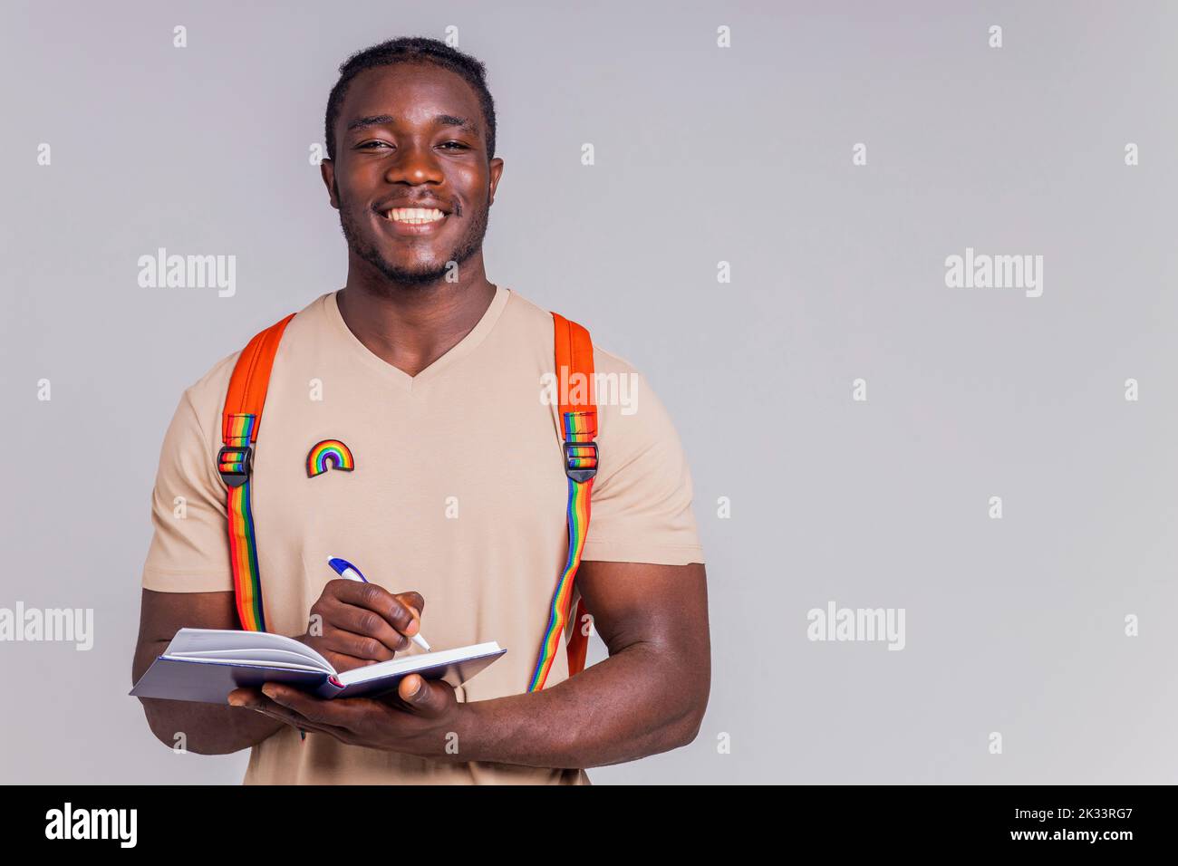 polyethnic man in beige t-shirt with an orange backpack holding book ...